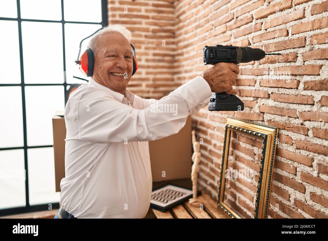 Senior man smiling confident drilling wall at new home Stock Photo - Alamy