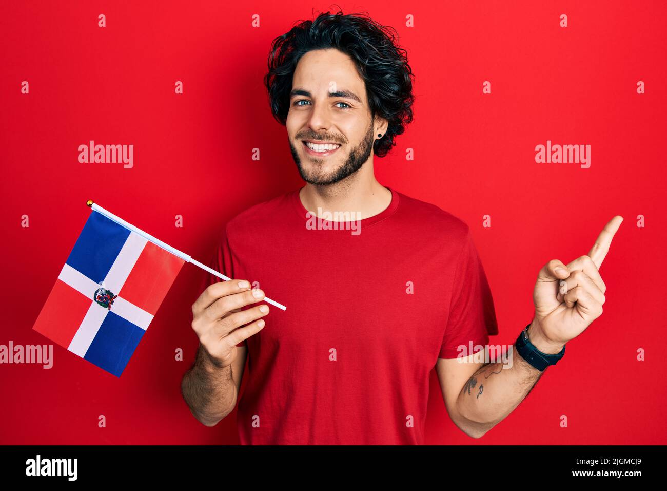 Handsome hispanic man holding dominican republic flag smiling happy ...
