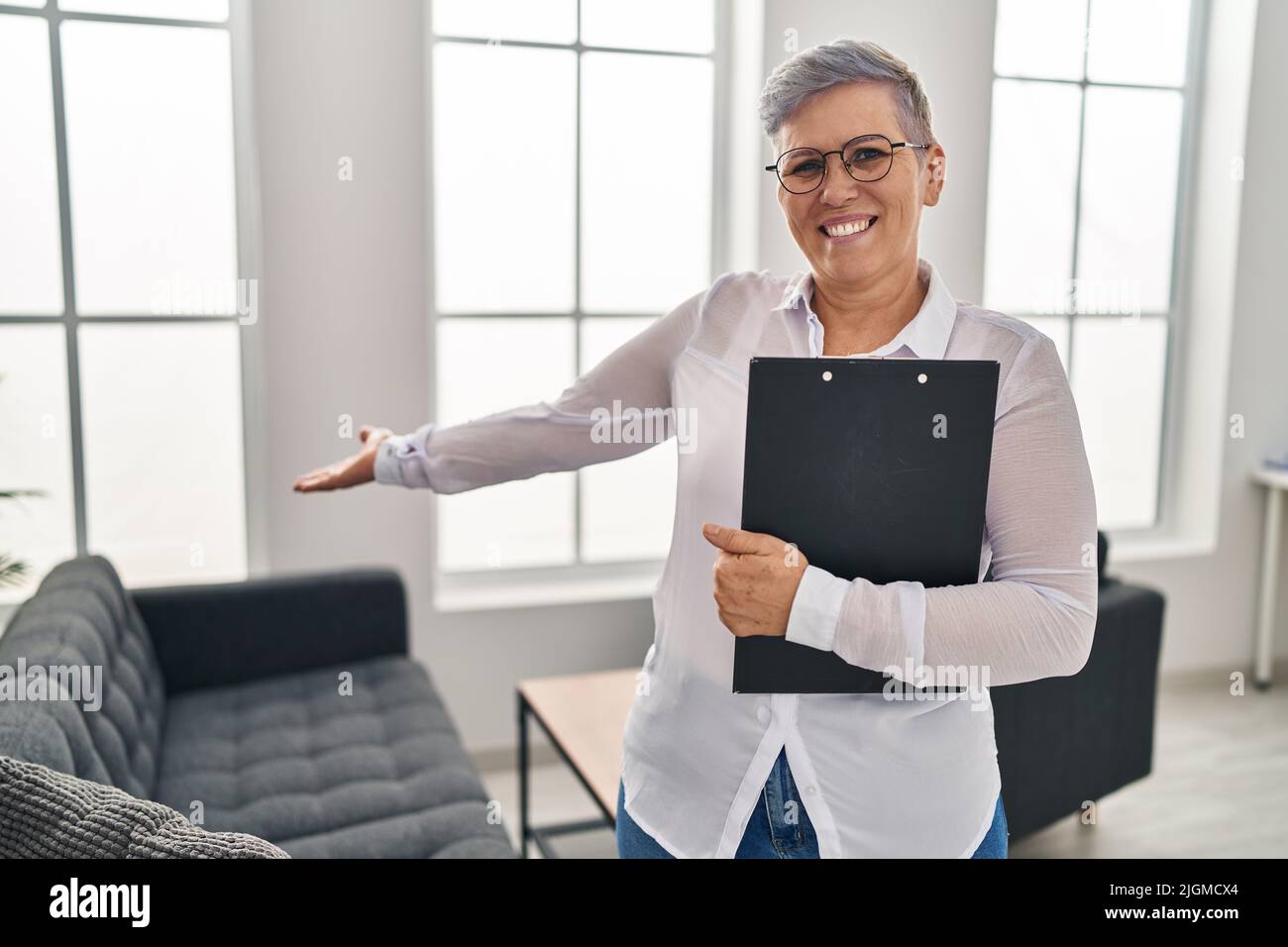 Middle age woman psychologist holding clipboard standing at pyschology ...