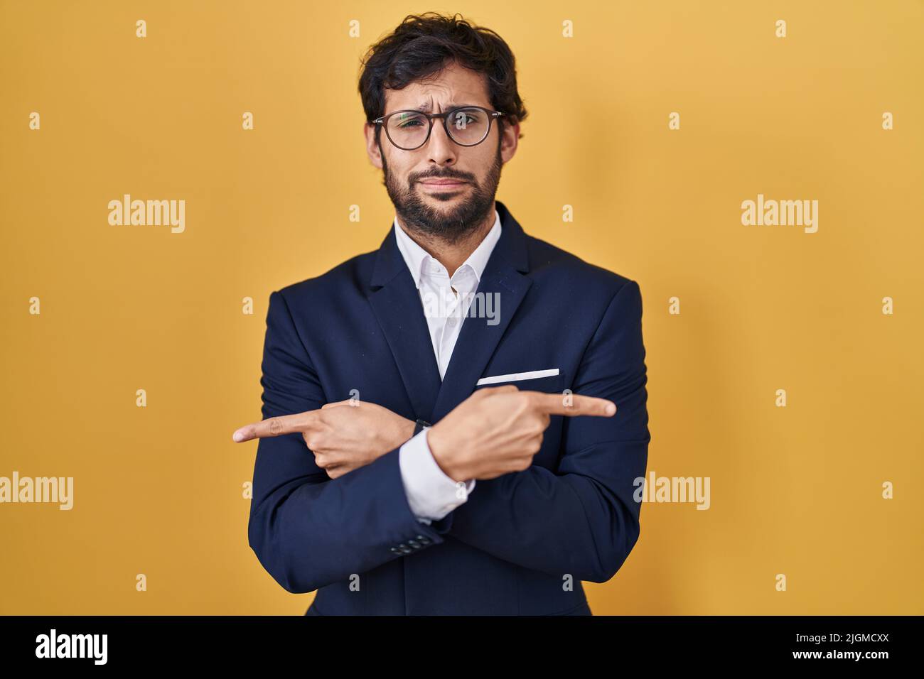 Handsome latin man standing over yellow background pointing to both ...