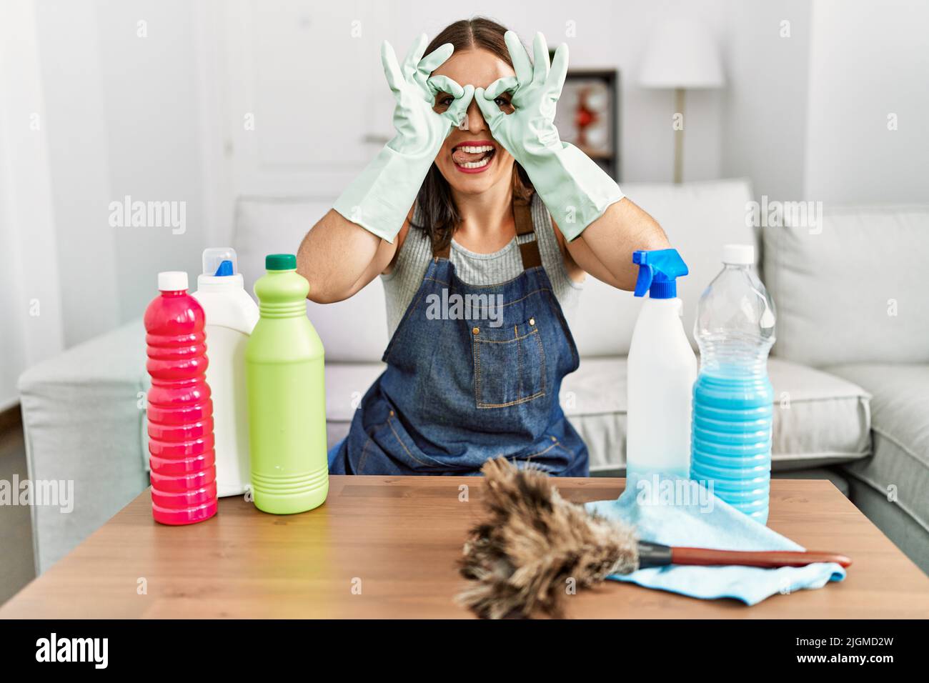 Young brunette woman wearing cleaner apron and gloves cleaning at home ...