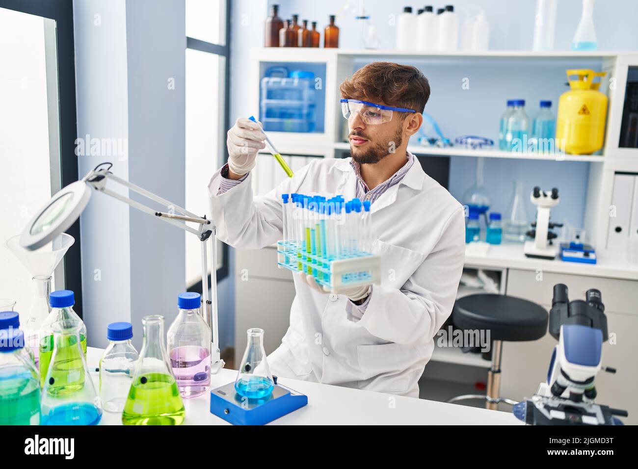 Young arab man scientist measuring liquid holding test tubes at ...