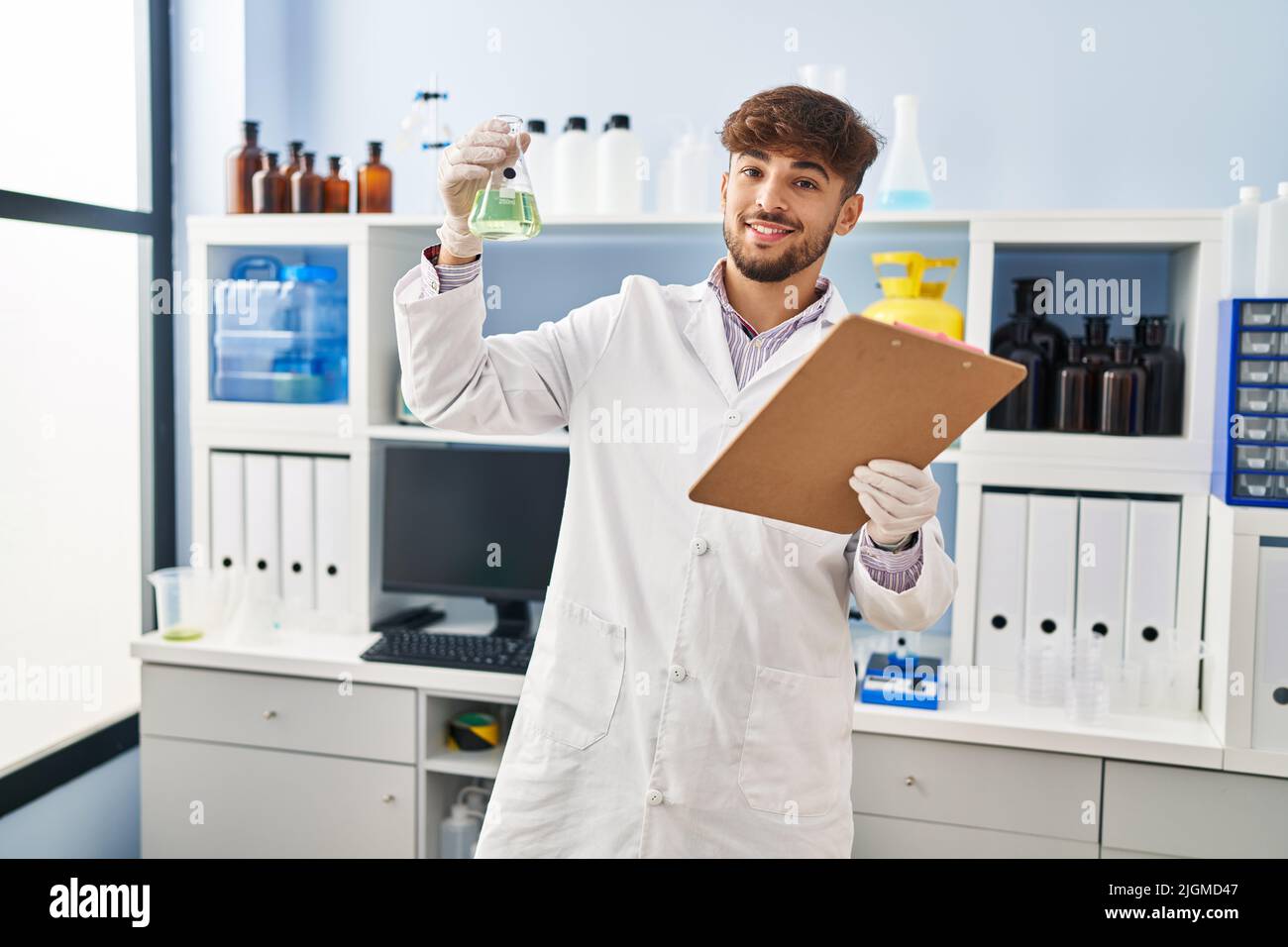Young arab man scientist measuring liquid reading report at laboratory Stock Photo - Alamy