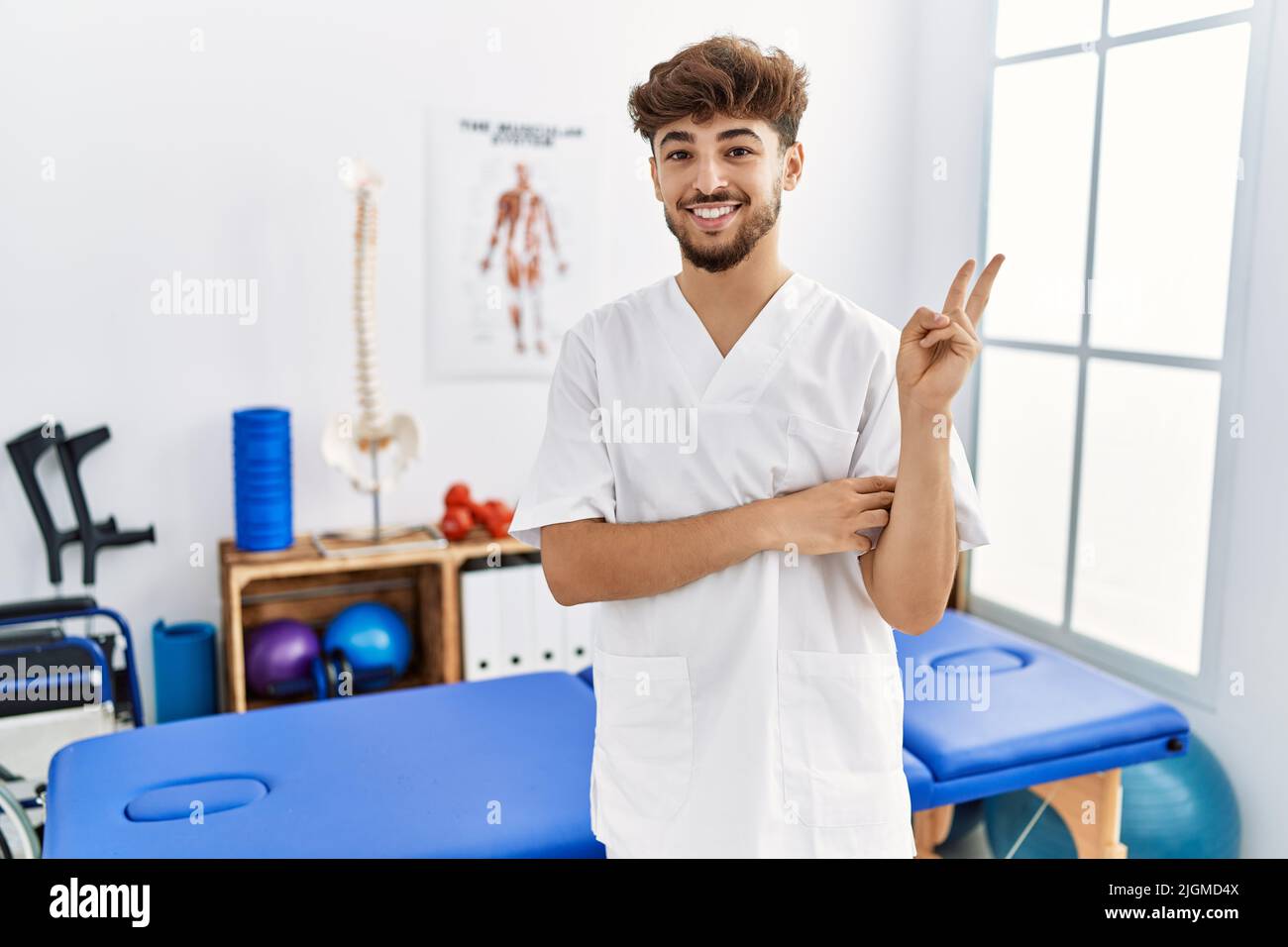 Young arab man working at pain recovery clinic smiling with happy face ...