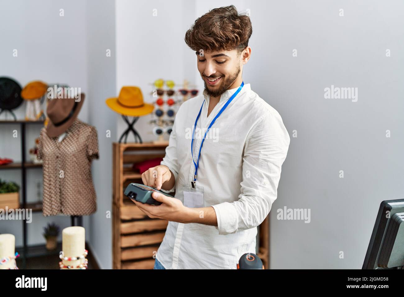 Young arab man smiling confident using data phone device at clothing ...