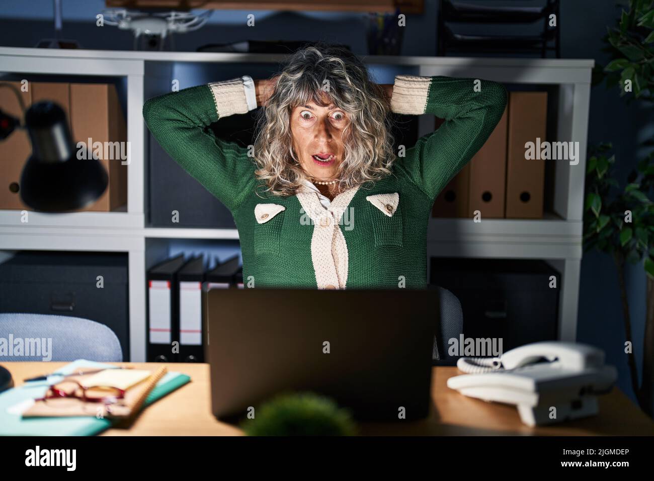 Middle age woman working at night using computer laptop crazy and ...