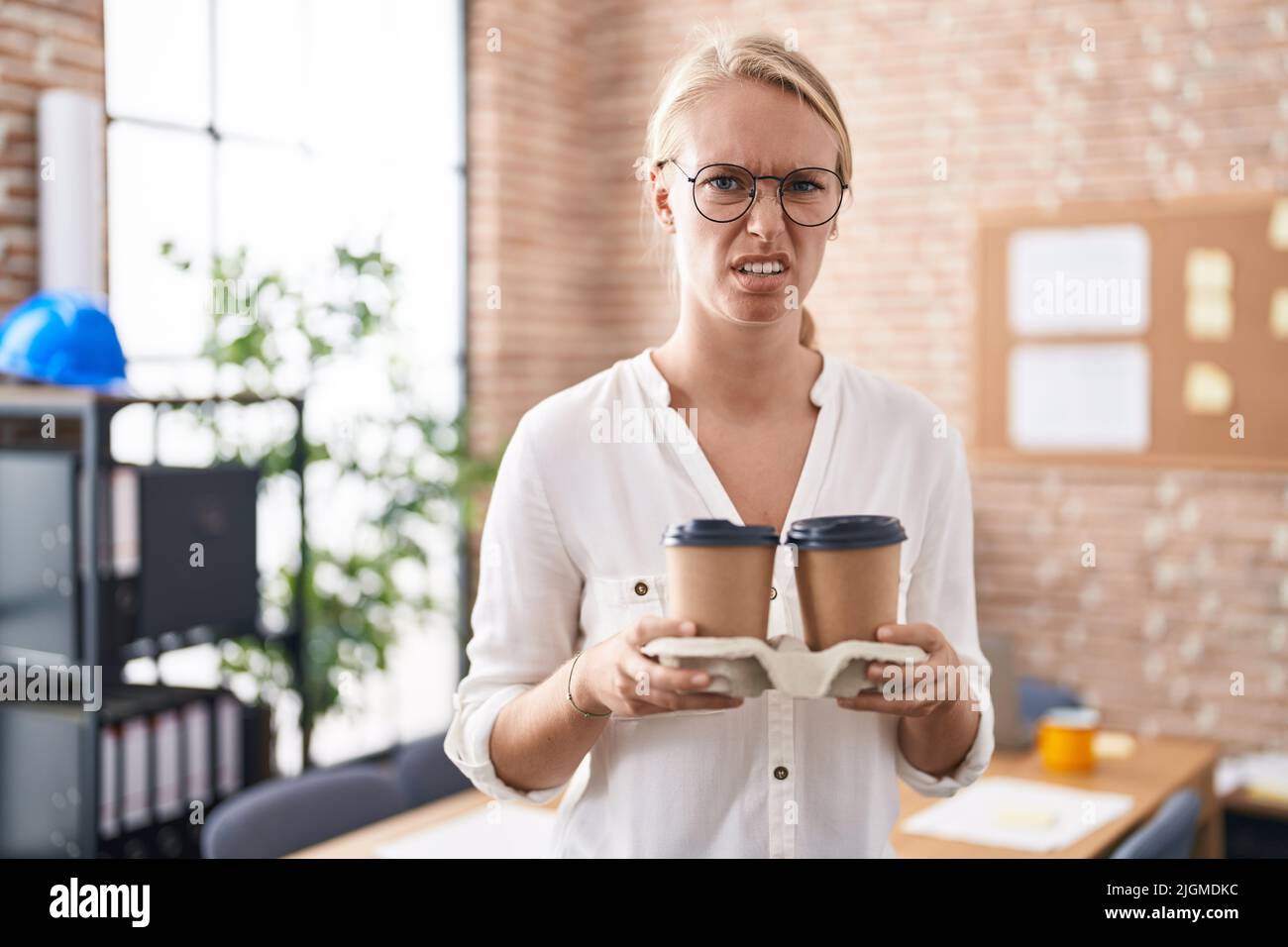Young caucasian woman working at the office holding coffee cups ...