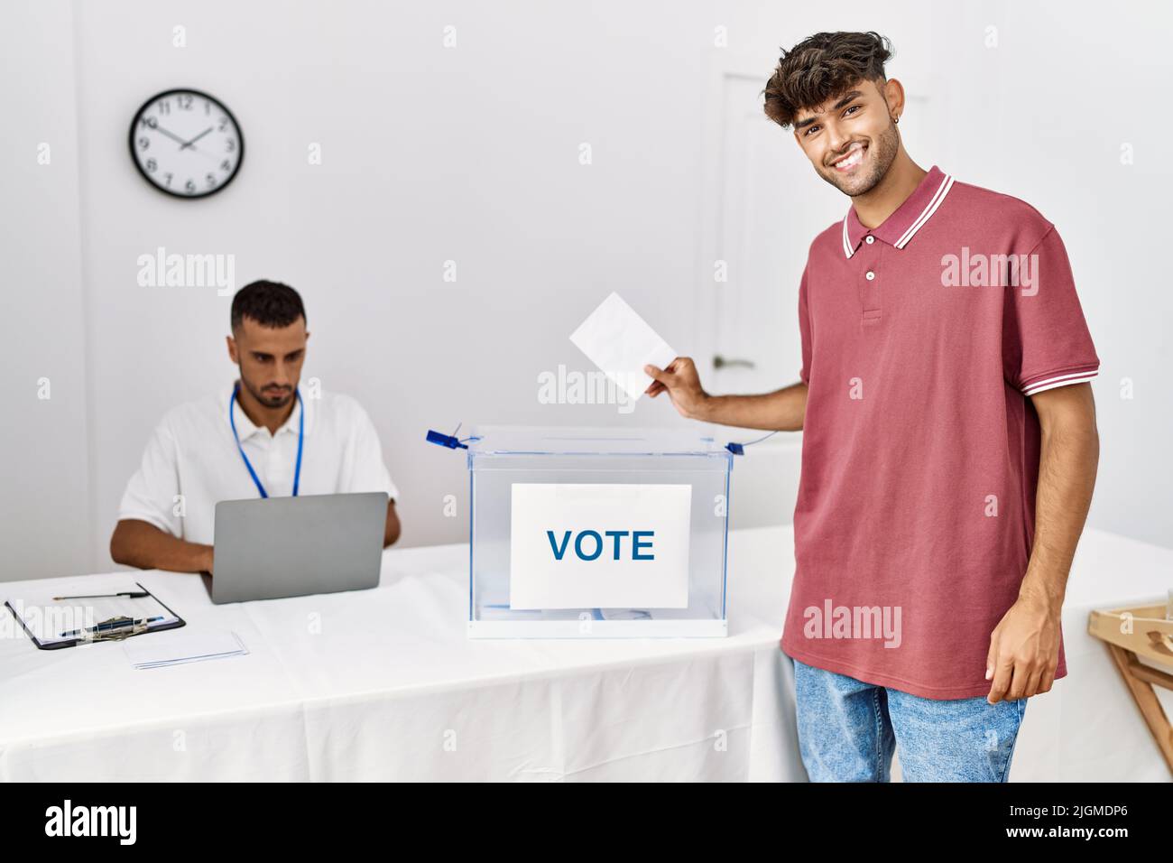 Young hispanic voter man smiling happy putting vote in ballot box at ...