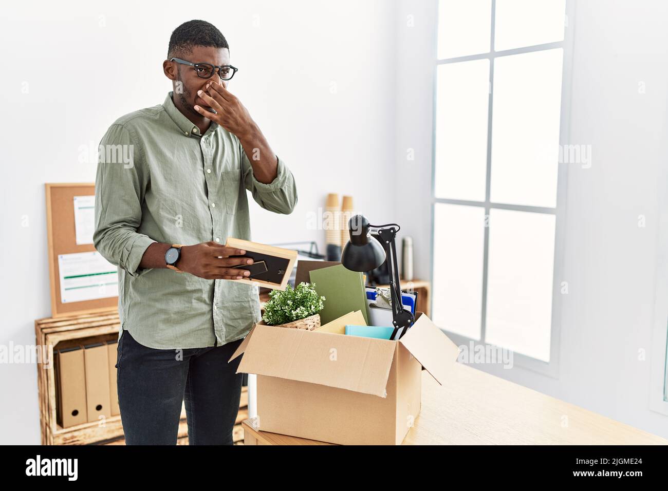 Young african american businessman unboxing box at the office smelling ...