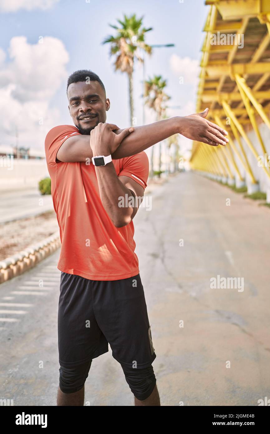 Young african american man wearing sportswear stretching at street ...
