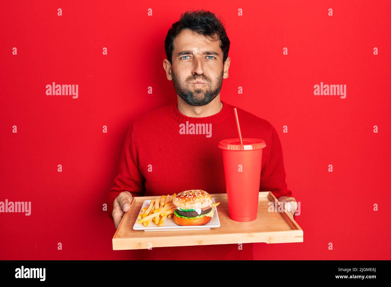 Handsome man with beard eating a tasty classic burger with fries and ...