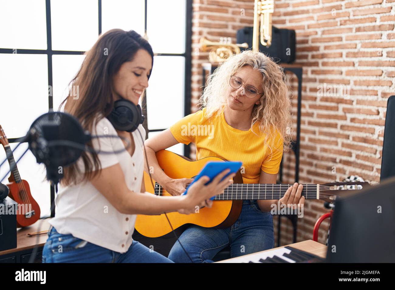 Two women musicians playing classical guitar looking touchpad at music ...