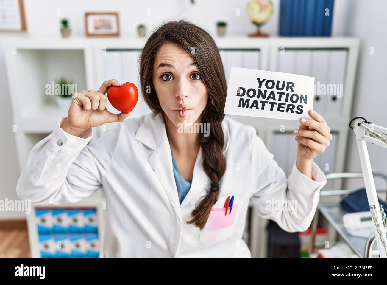 Young doctor woman holding your donation matters banner at the clinic ...