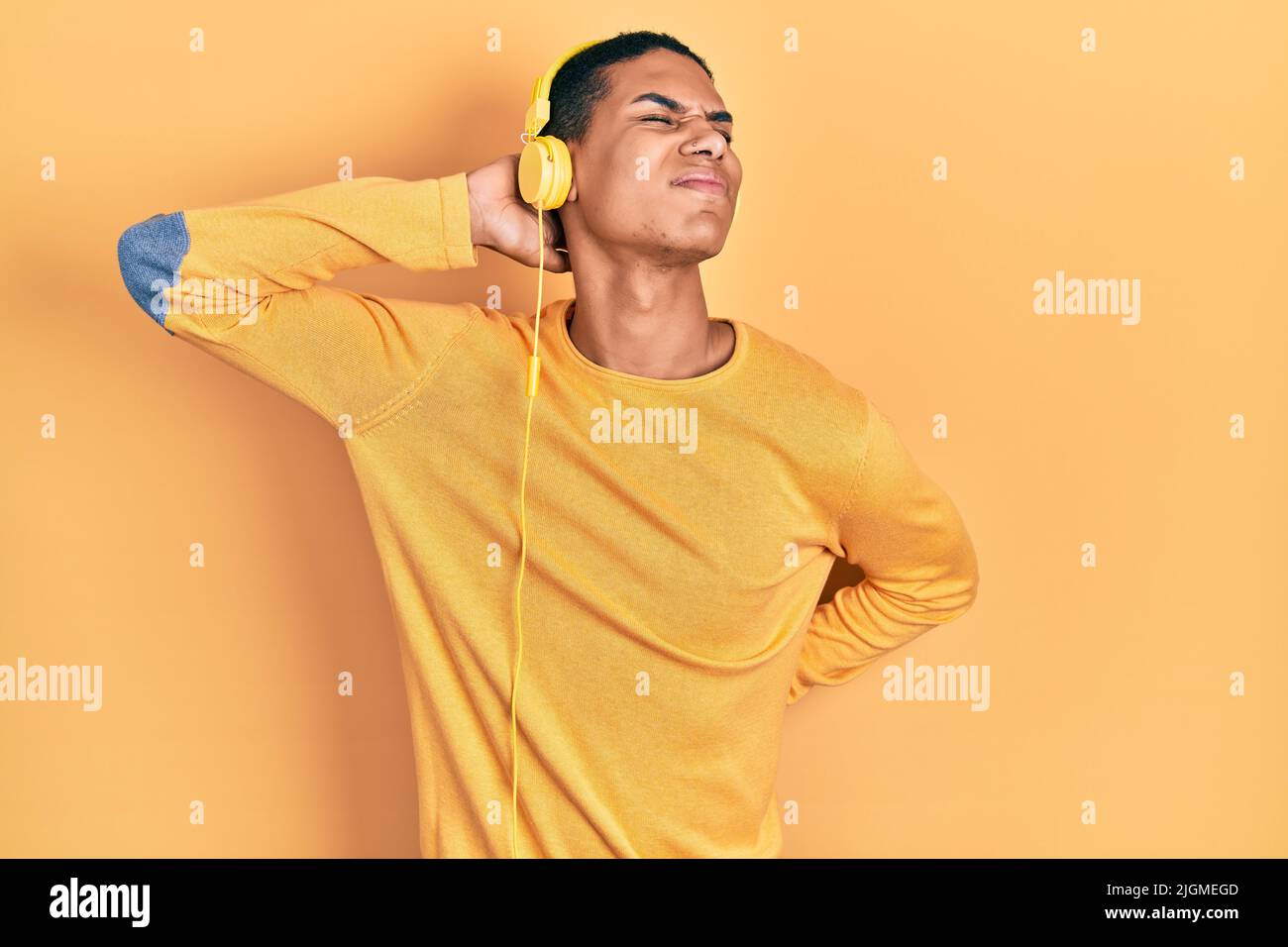 Young african american guy listening to music using headphones ...