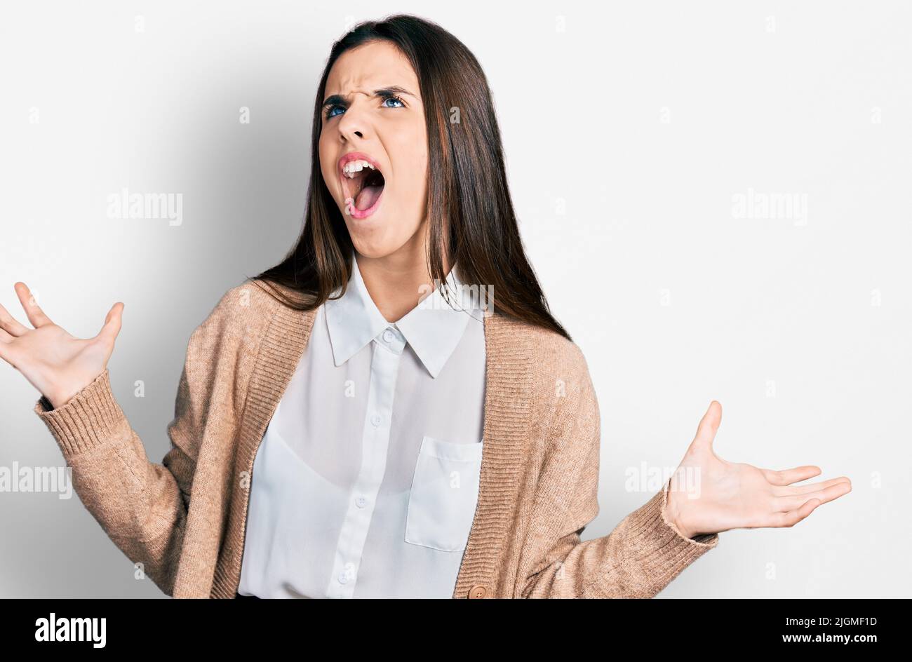 Young brunette teenager wearing casual white shirt and jacket crazy and ...