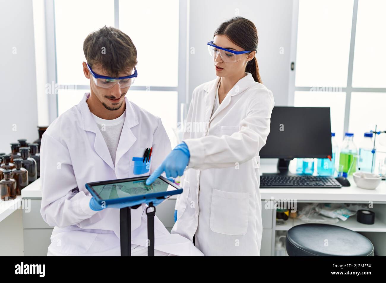 Man and woman partners wearing scientist uniform using touchpad with ...