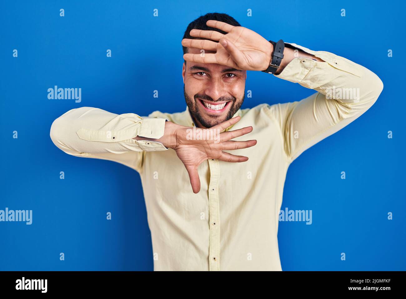 Handsome hispanic man standing over blue background smiling cheerful ...