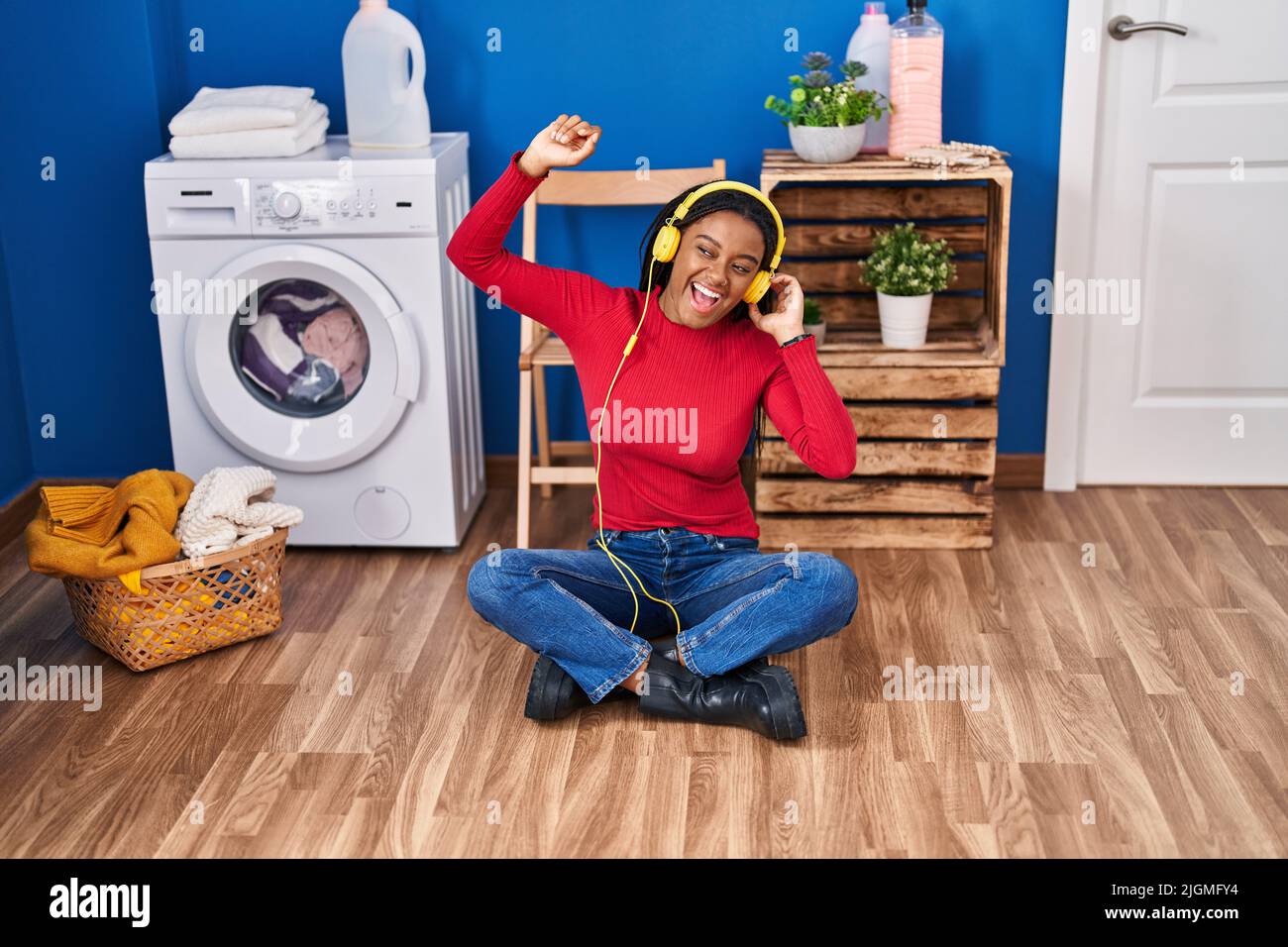 African american woman listening to music waiting for washing machine ...