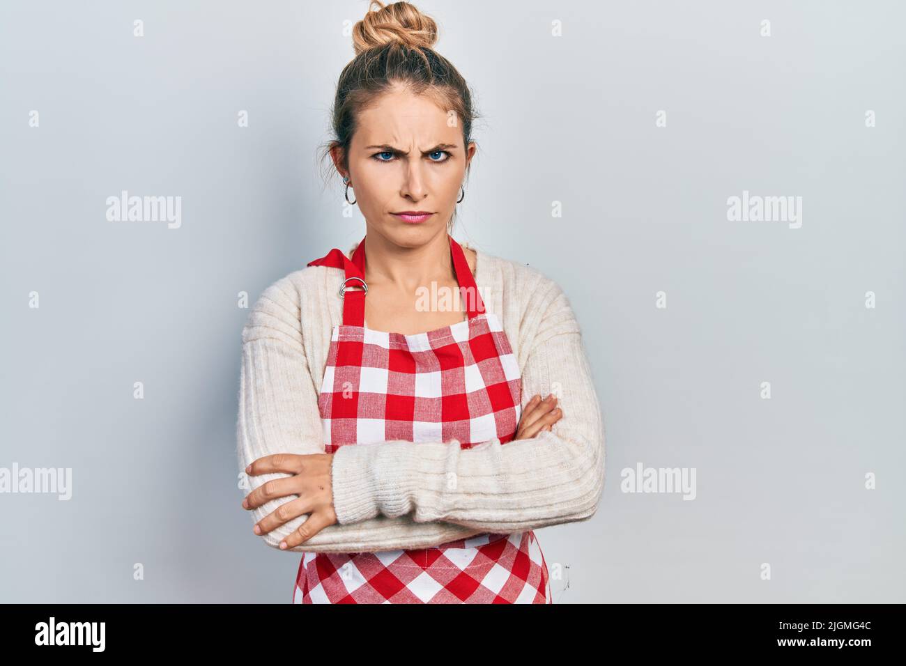 Beautiful caucasian woman with blond hair wearing apron skeptic and ...