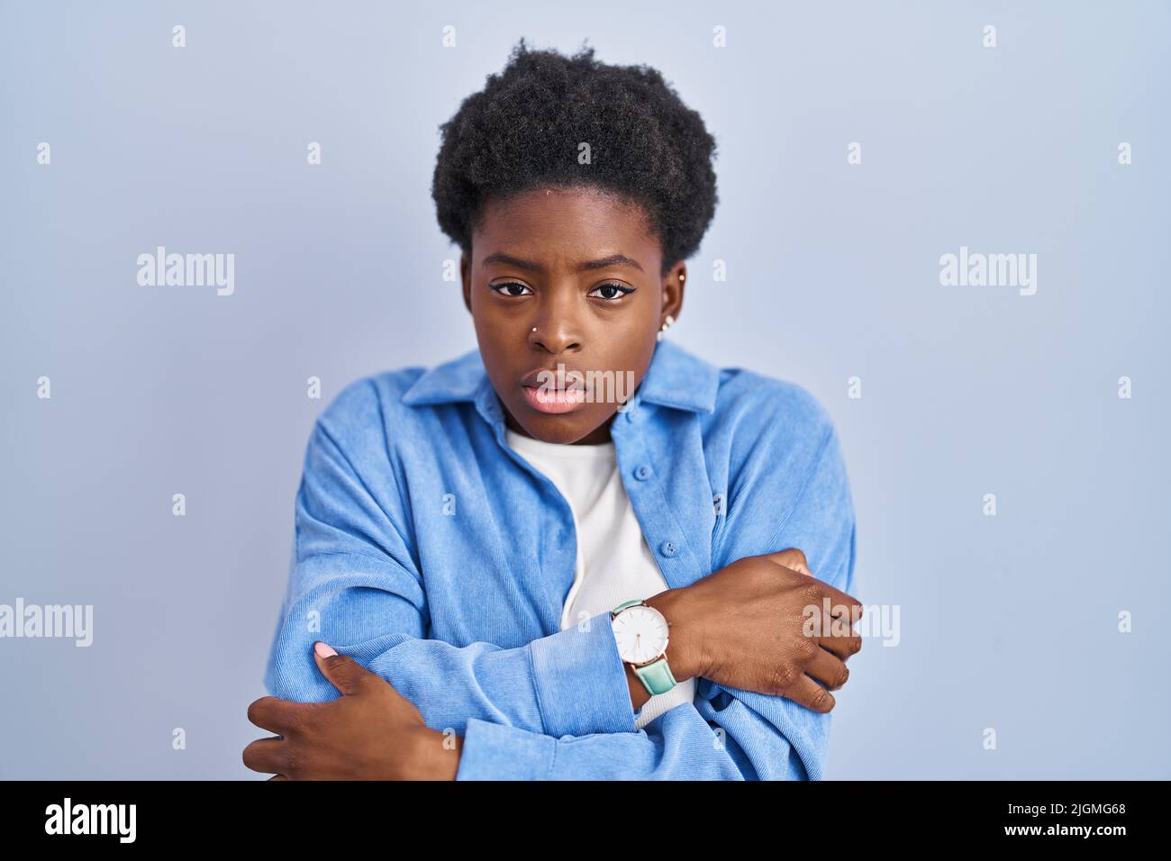 African american woman standing over blue background shaking and ...