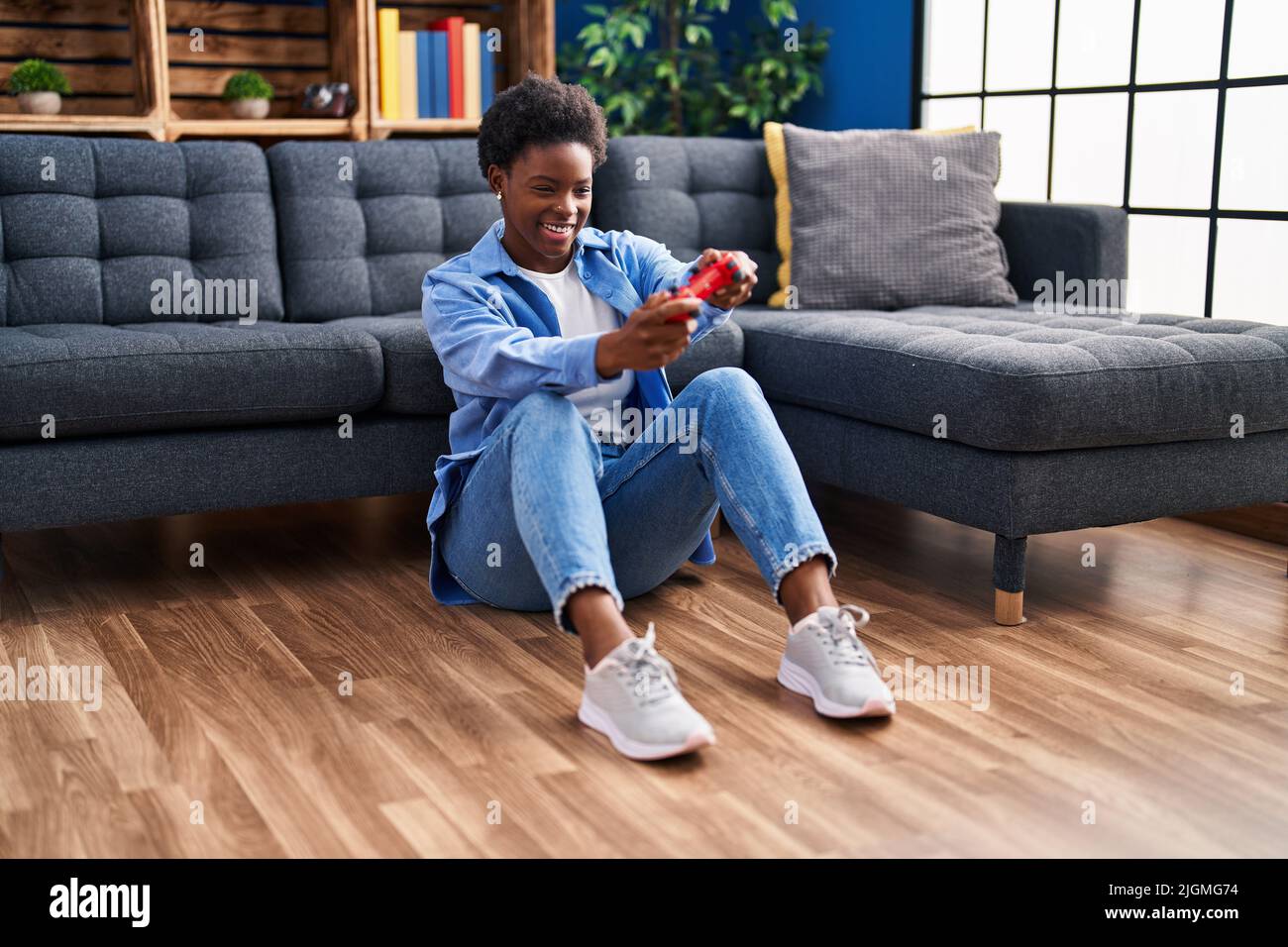 African american woman playing video game sitting on floor at home ...