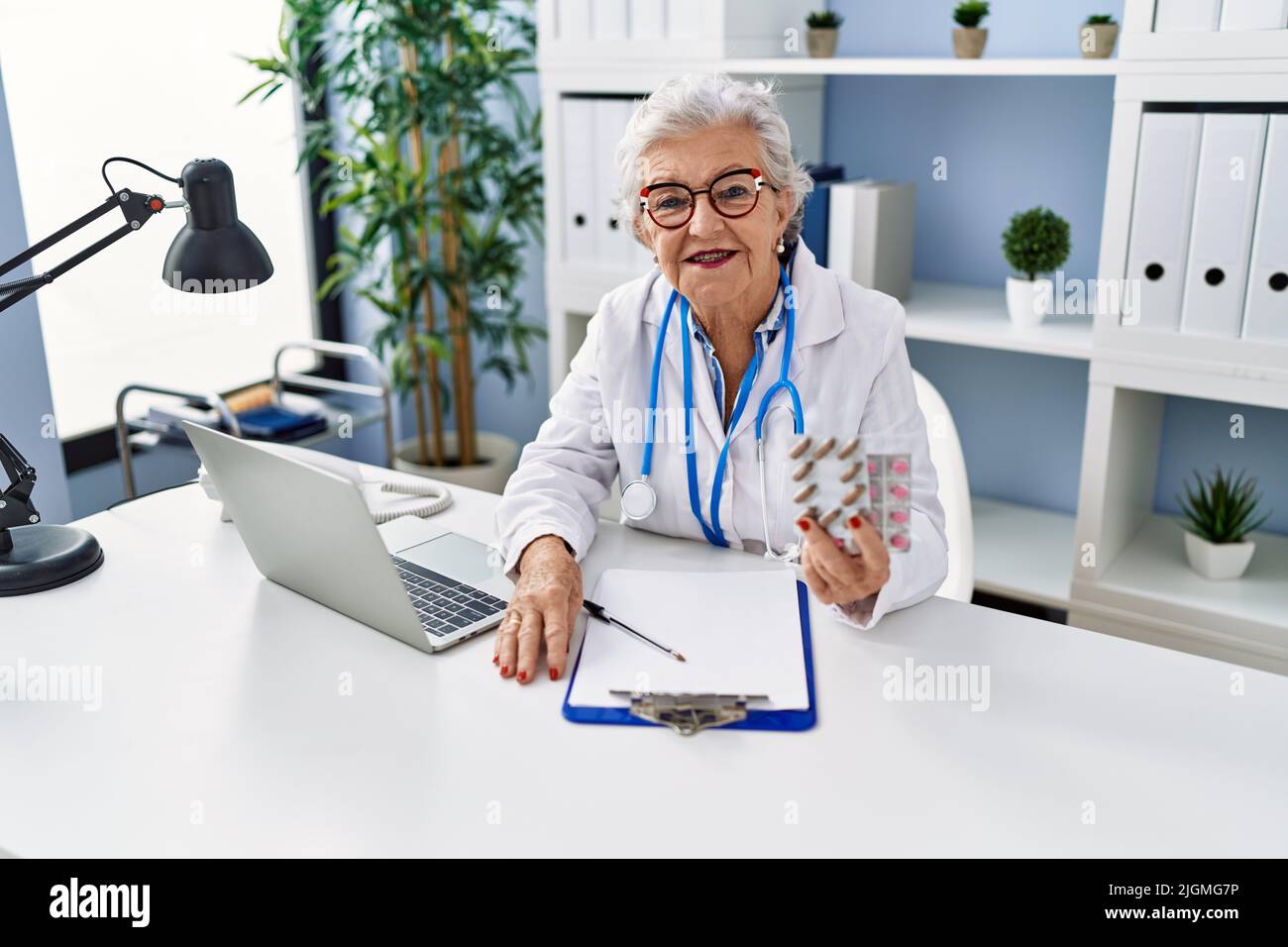 Senior woman with grey hair wearing doctor uniform holding prescription ...