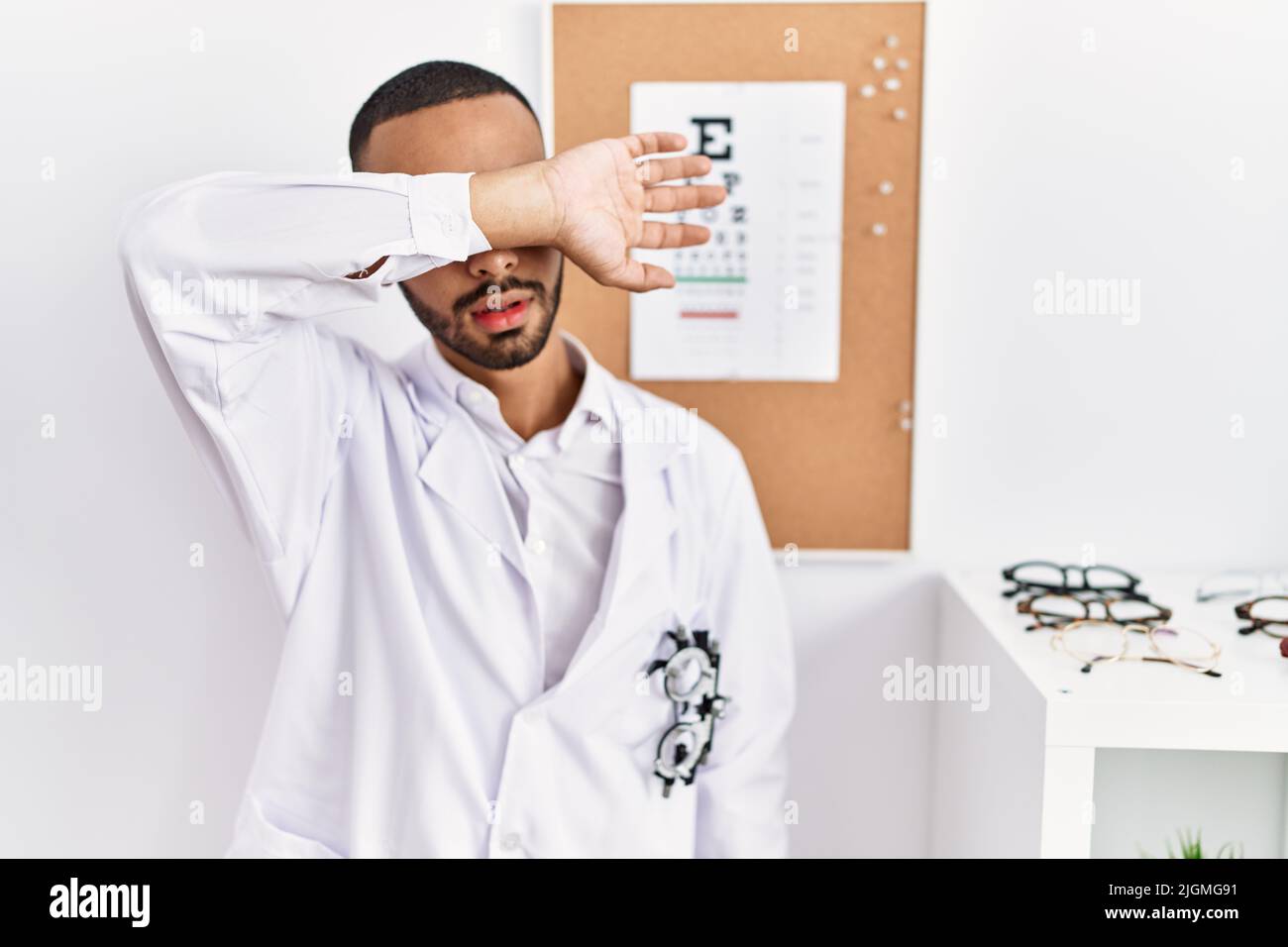 African american optician man standing by eyesight test covering eyes ...