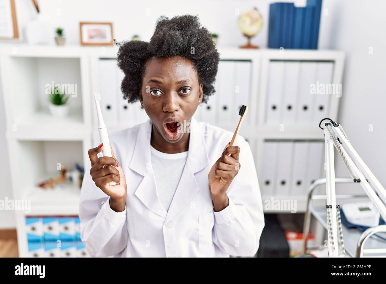 African dentist woman holding electric toothbrush and normal toothbrush ...