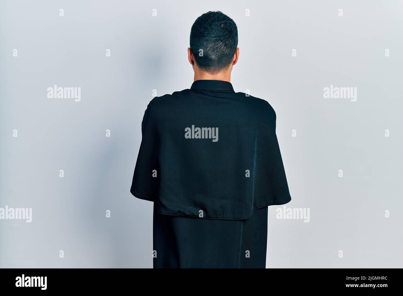 Handsome hispanic man with beard wearing catholic priest robe standing ...