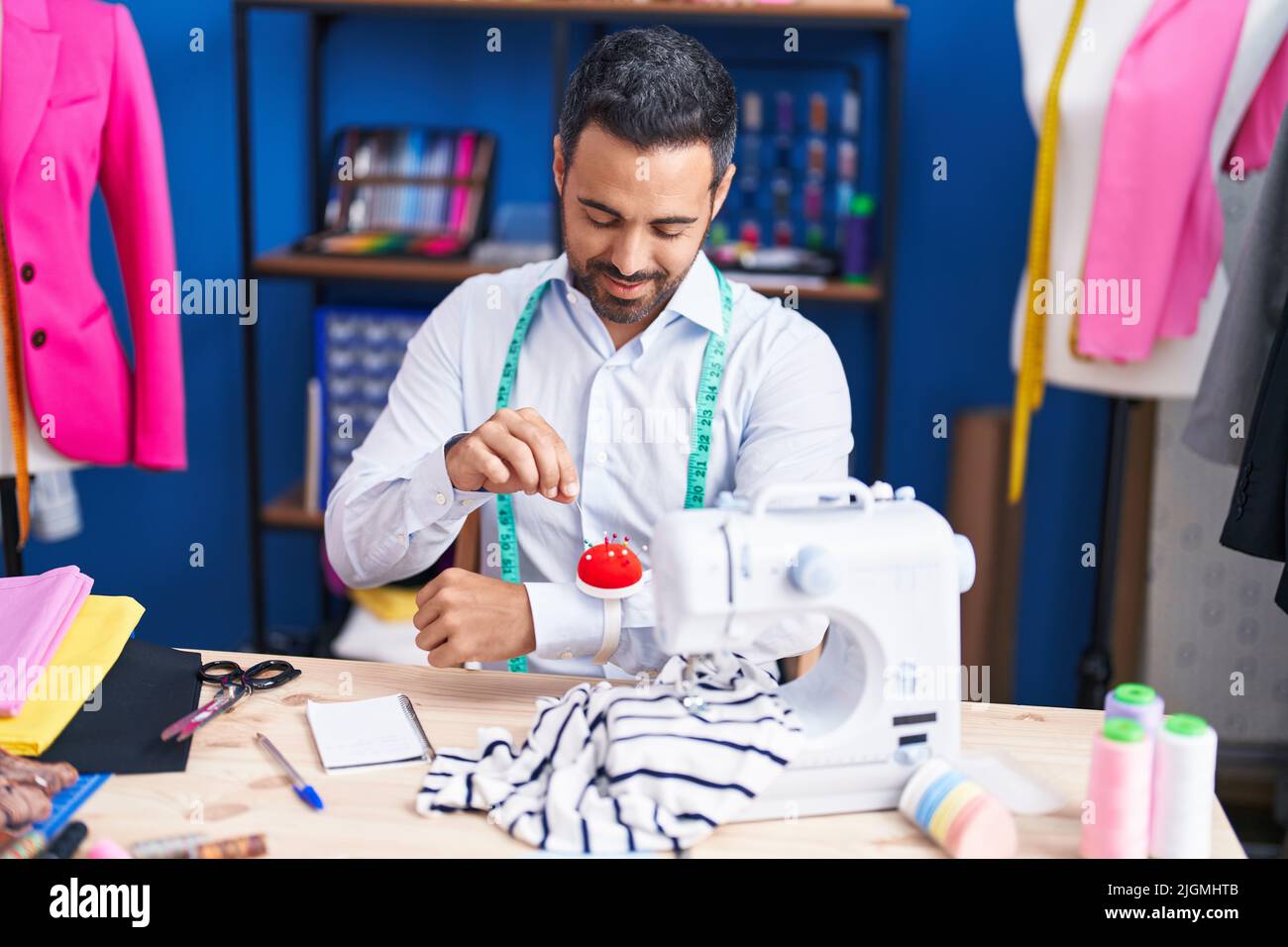Young hispanic man tailor smiling confident holding pin at sewing ...
