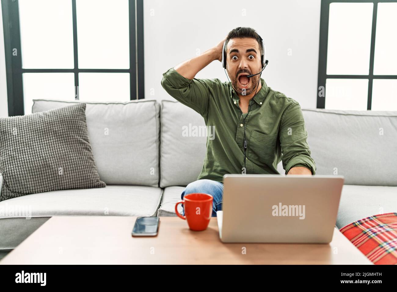 Young hispanic man with beard wearing call center agent headset working ...
