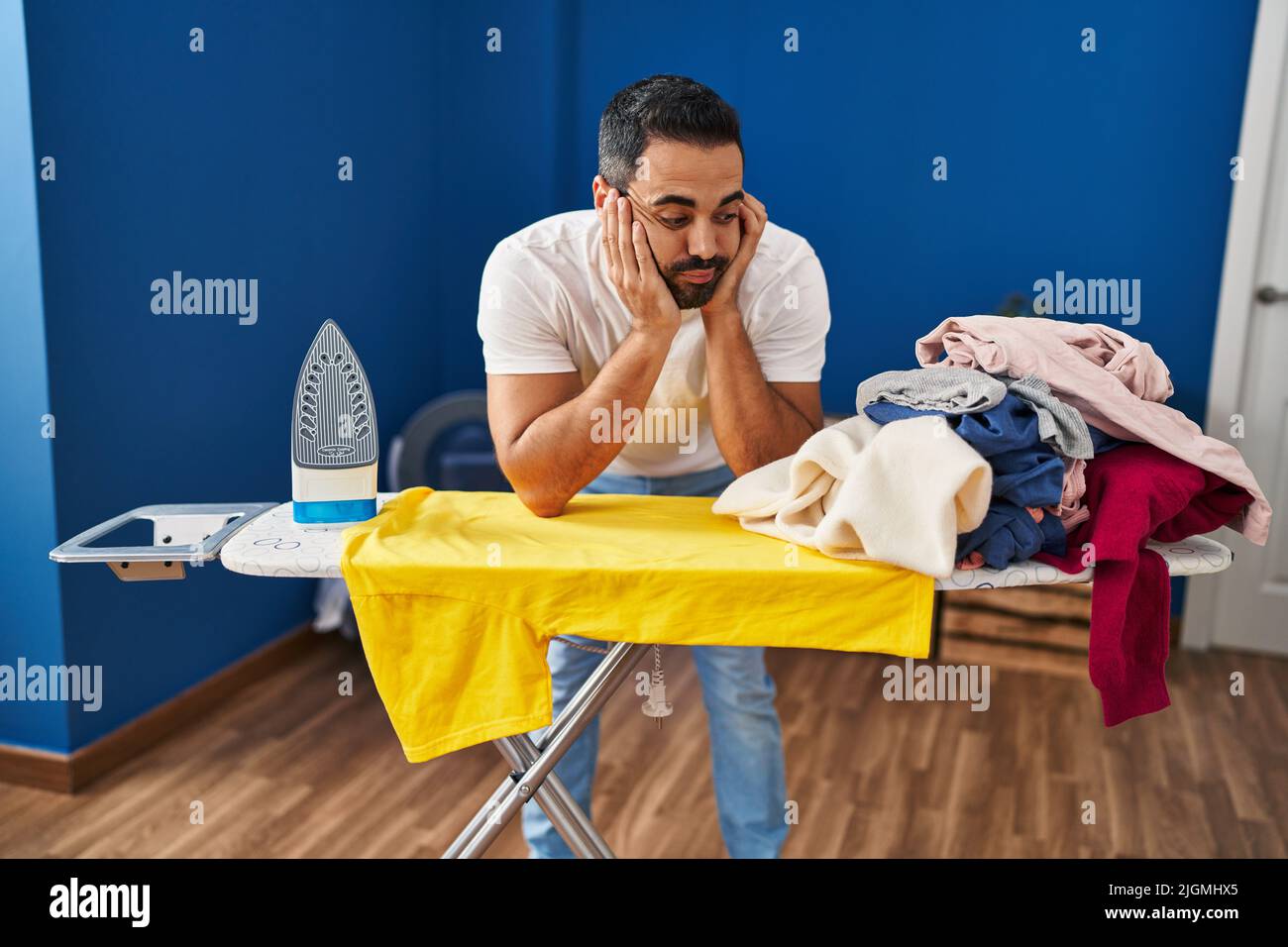 Young hispanic man tired leaning on ironing board at laundry room Stock ...