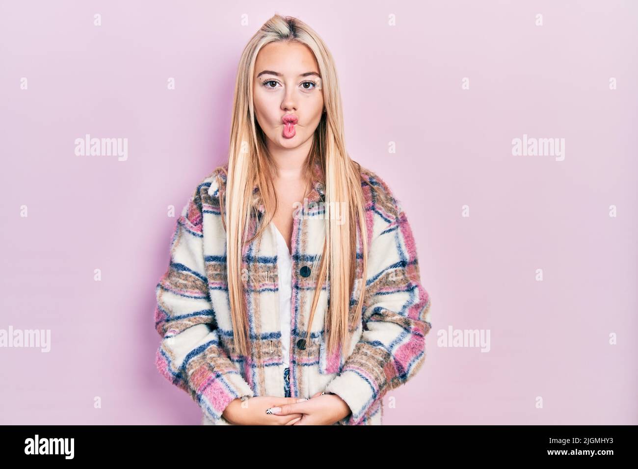 Young blonde girl wearing casual clothes making fish face with lips ...