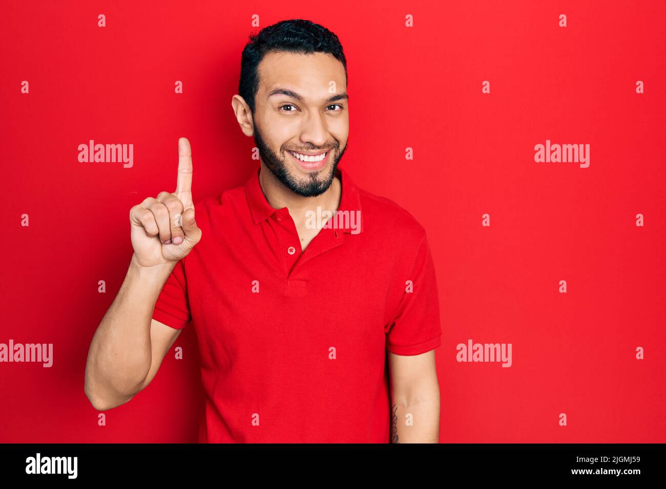 Hispanic man with beard wearing casual red t shirt showing and pointing ...