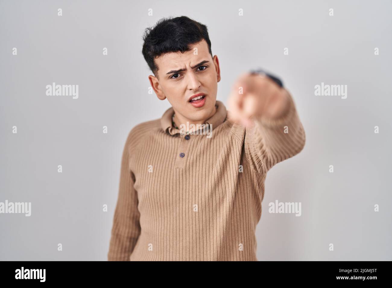 Non binary person standing over isolated background pointing displeased ...