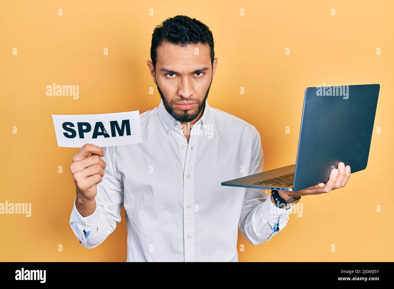 Hispanic man with beard working using computer laptop holding spam ...