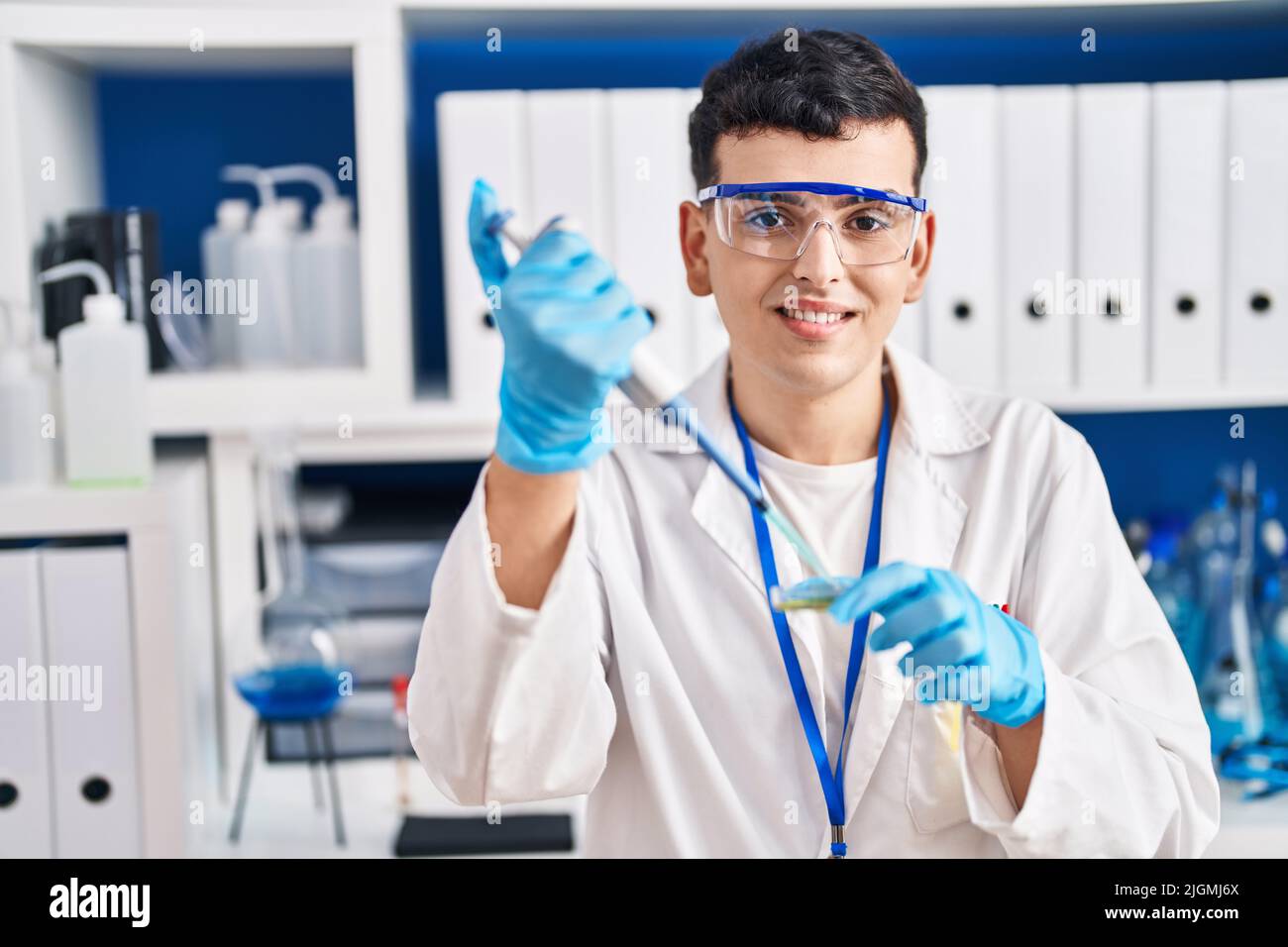 Young non binary man scientist smiling confident using pipette at laboratory Stock Photo - Alamy