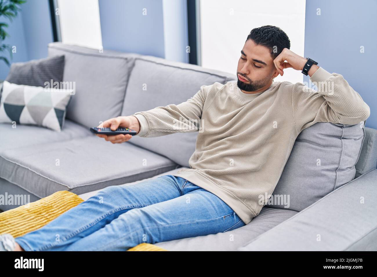 Young arab man watching tv with boring expression at home Stock Photo ...