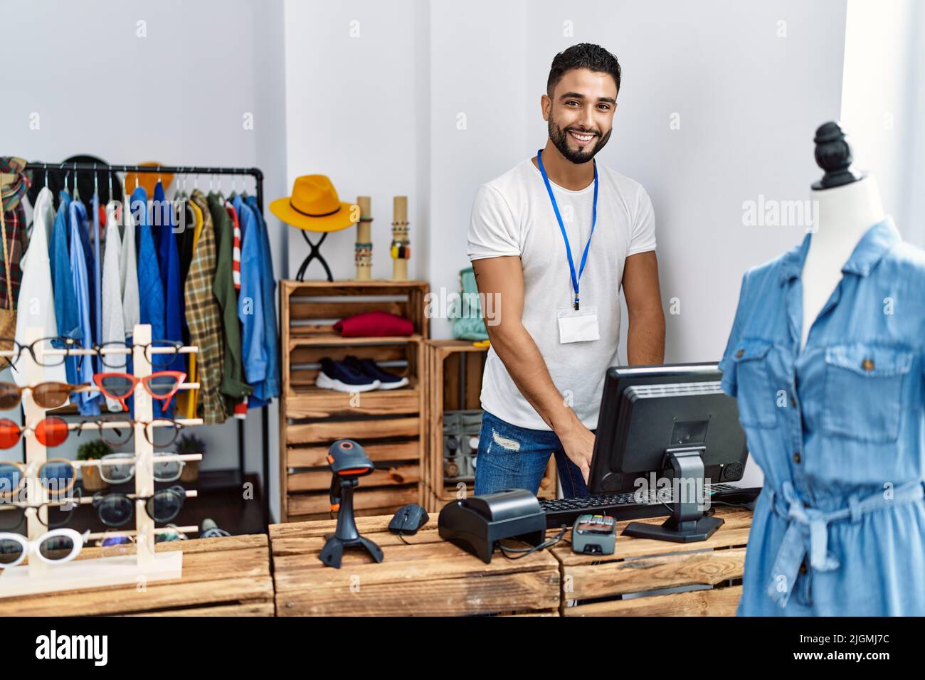 Young arab man shopkeeper smiling confident working at clothing store ...