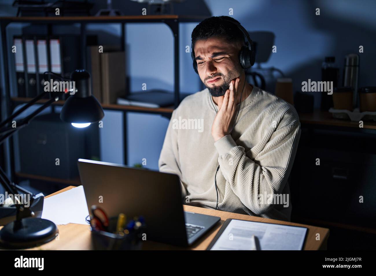 Young handsome man working using computer laptop at night touching ...