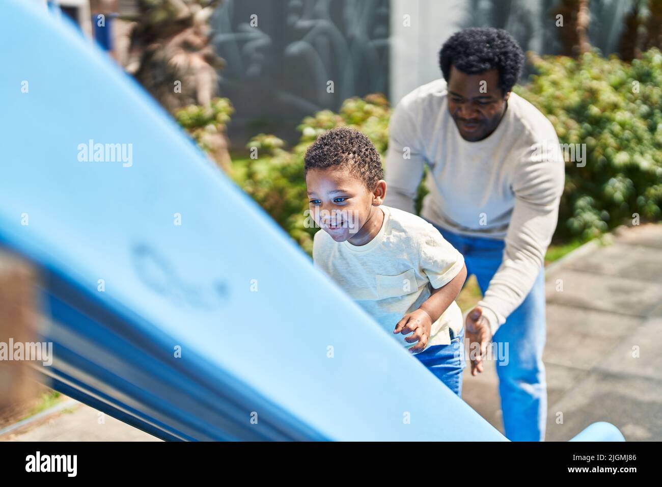 Father and son playing on slide at playground Stock Photo - Alamy