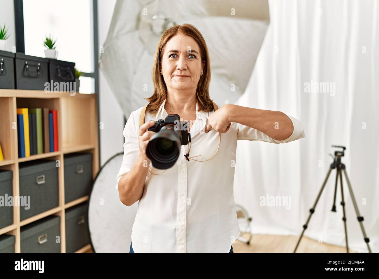 Middle age photography woman using camera at photo studio pointing ...