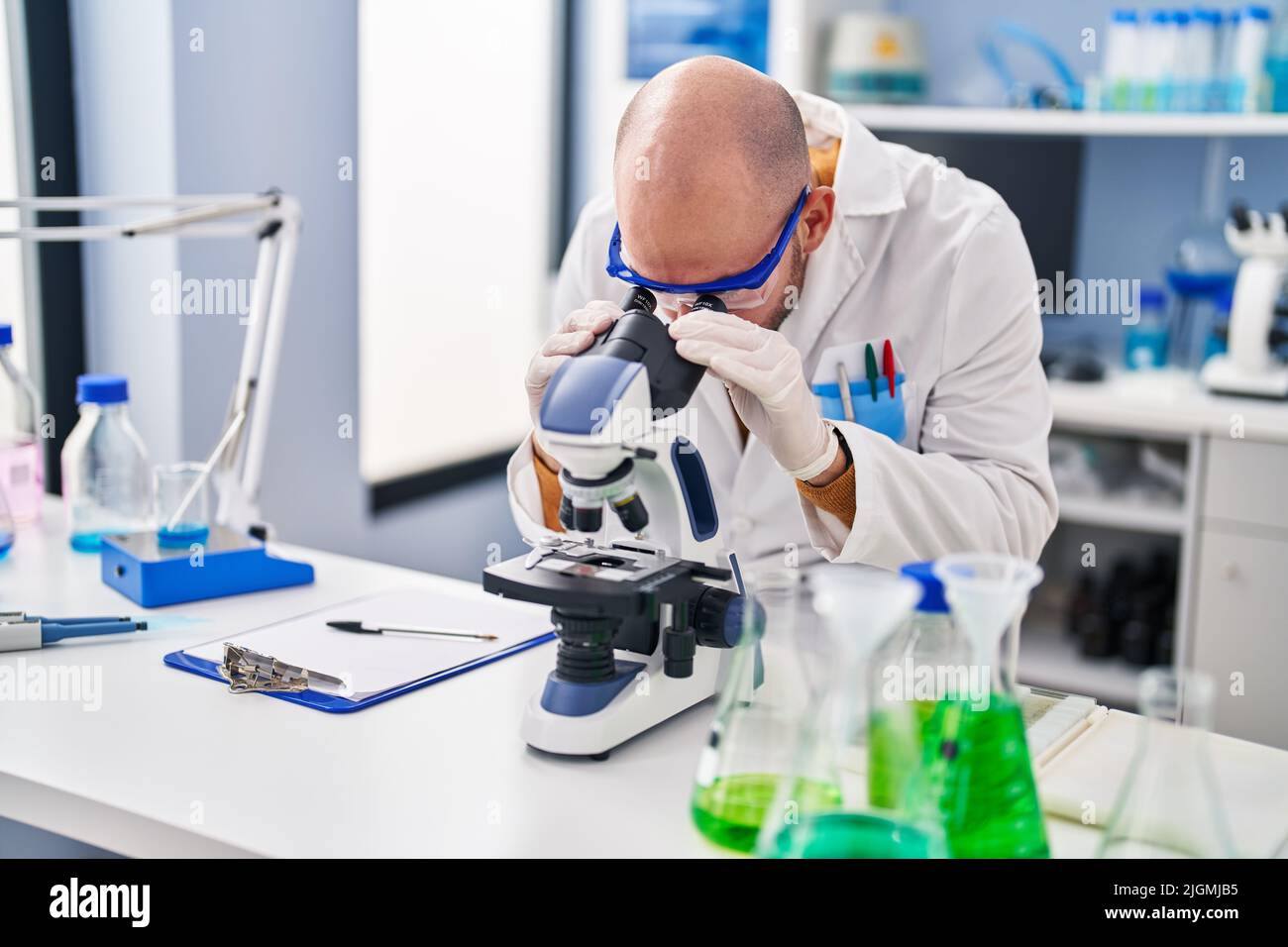 Young man scientist using microscope at laboratory Stock Photo - Alamy