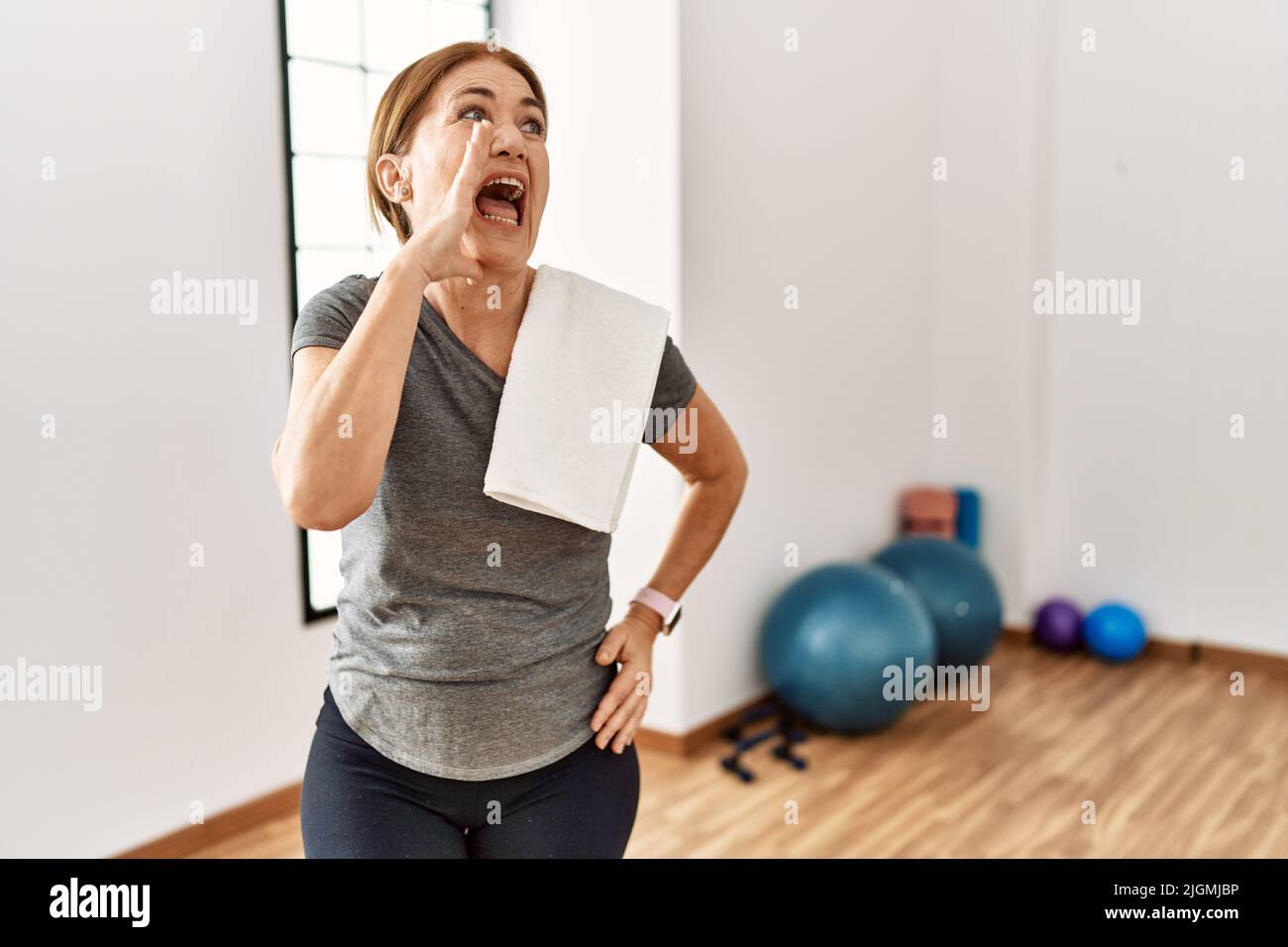 Middle age woman wearing sporty look training at the gym room shouting ...