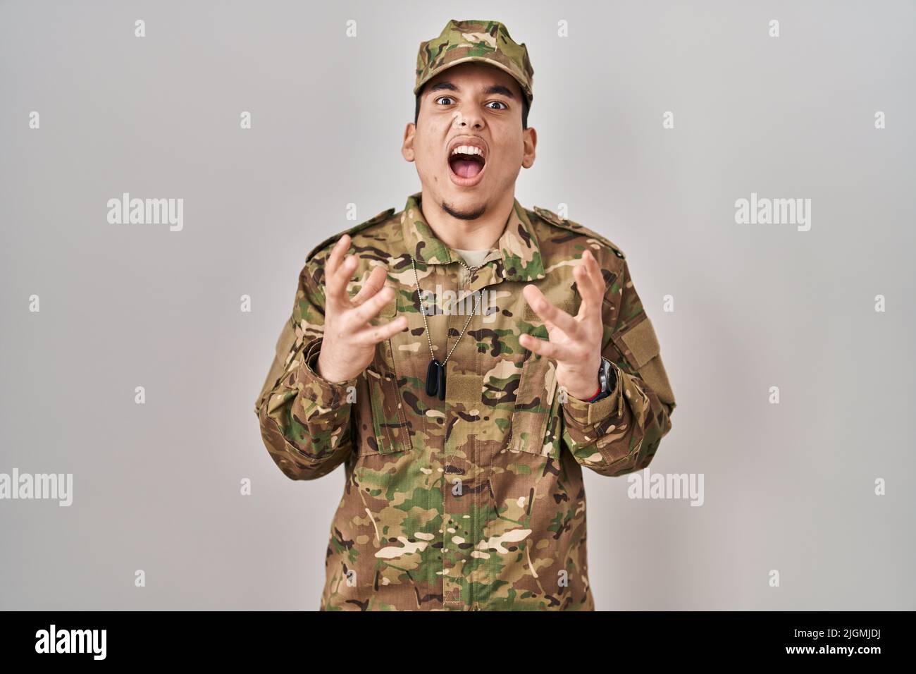 Young arab man wearing camouflage army uniform crazy and mad shouting ...