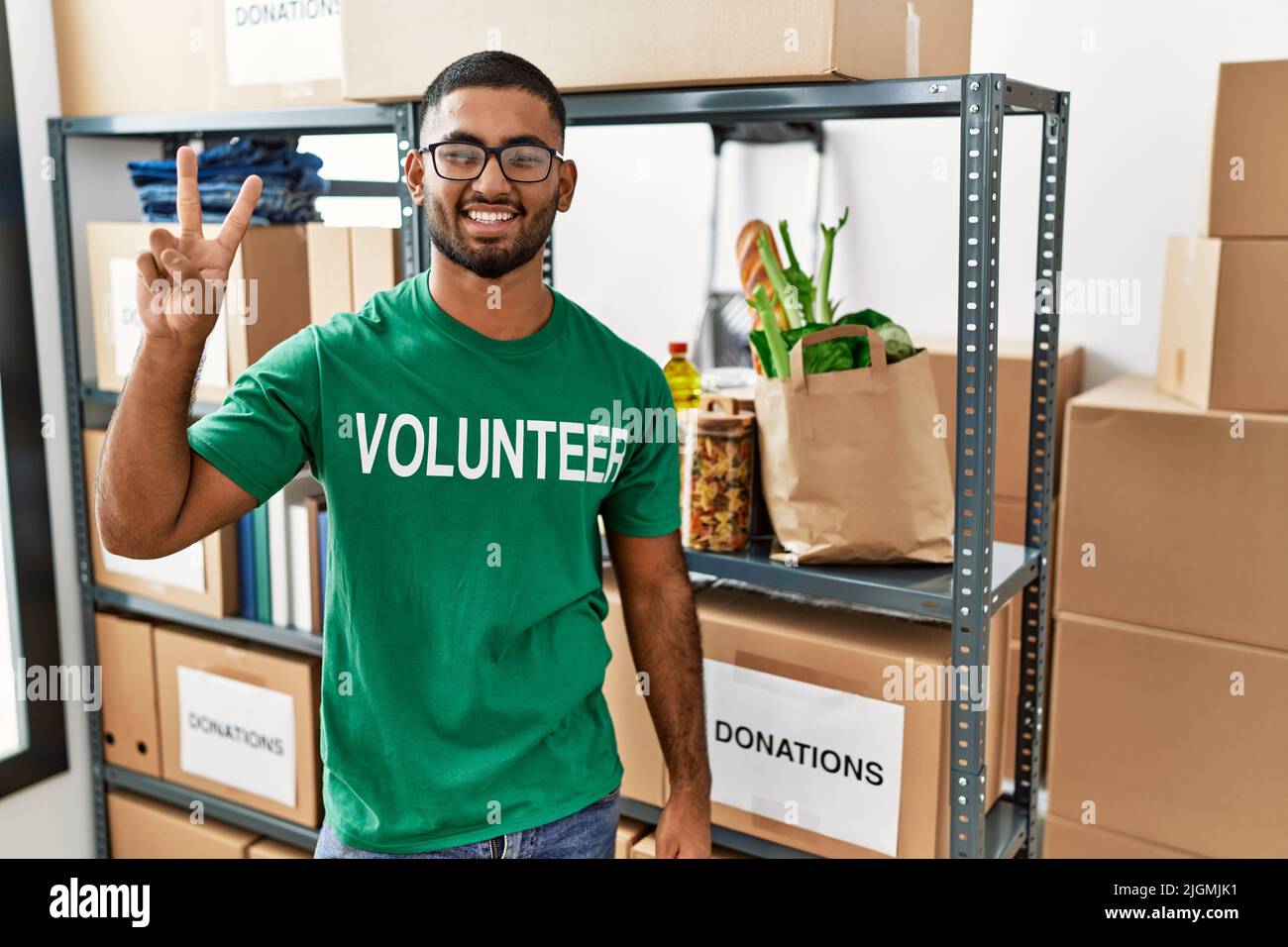 Young indian man volunteer holding donations box showing and pointing ...