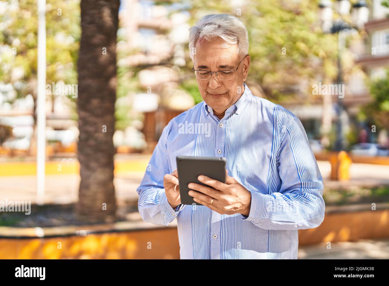 Senior man smiling confident using touchpad at park Stock Photo - Alamy