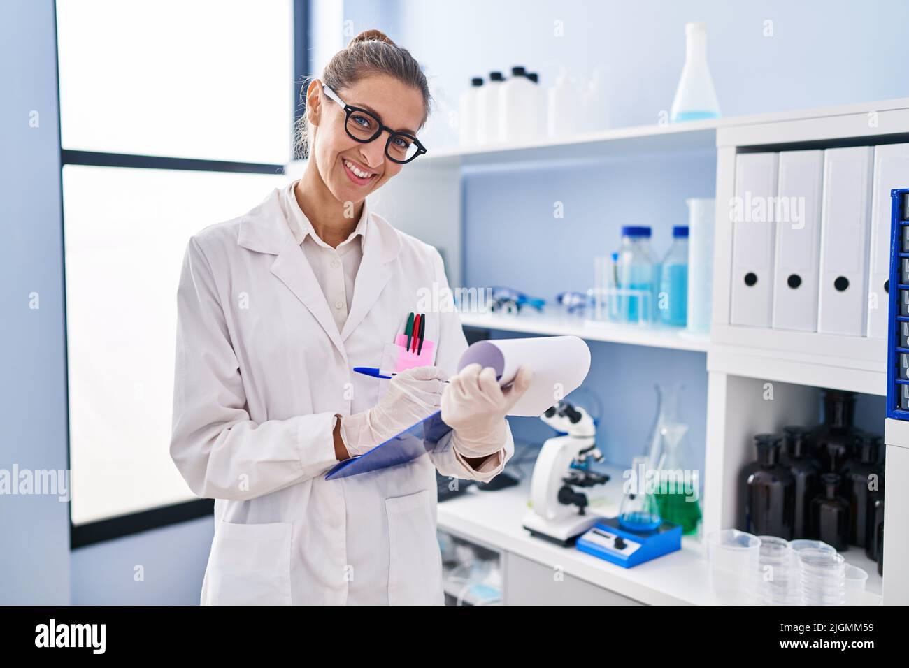 Young woman scientist writing on clipboard at laboratory Stock Photo - Alamy
