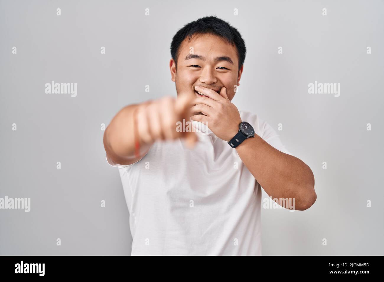 Young chinese man standing over white background laughing at you ...