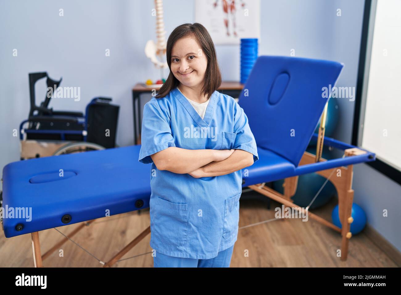 Down syndrome woman wearing physiotherapy uniform standing with arms ...